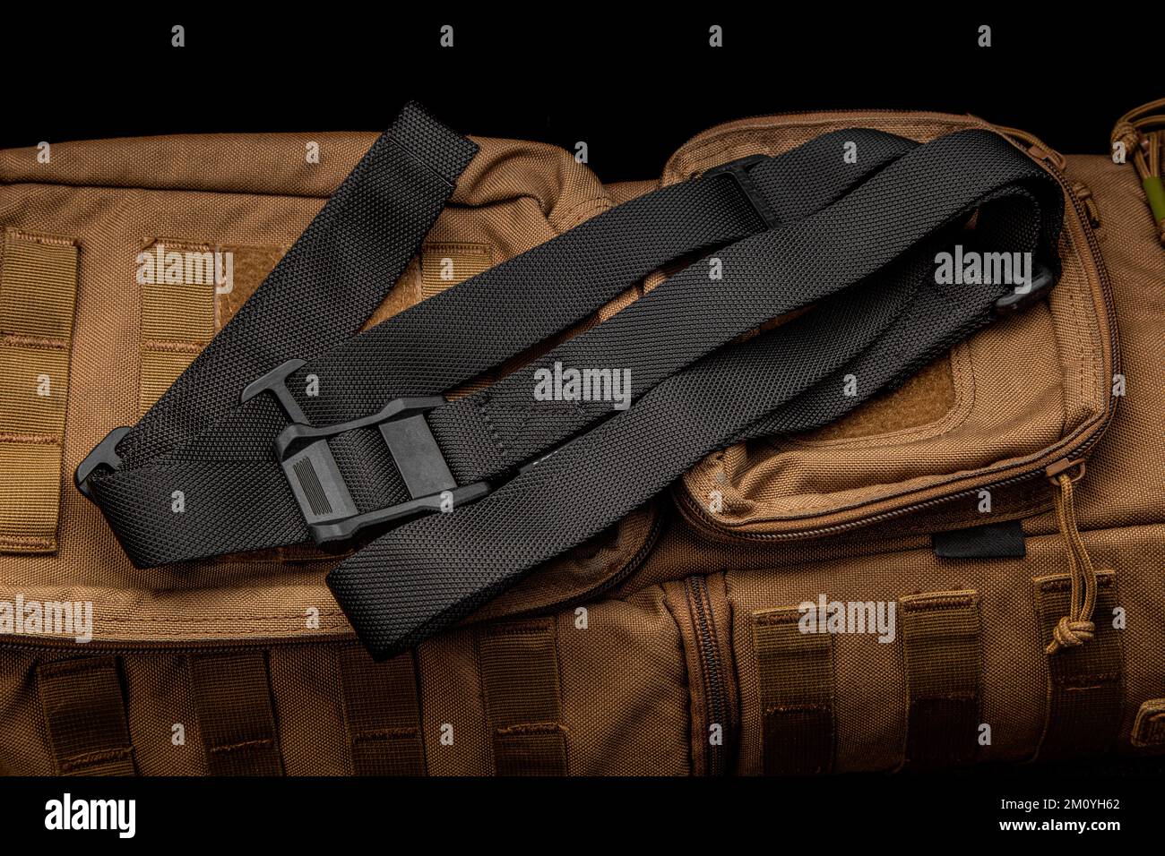 A black nylon weapon belt on a brown military backpack. Dark background ...