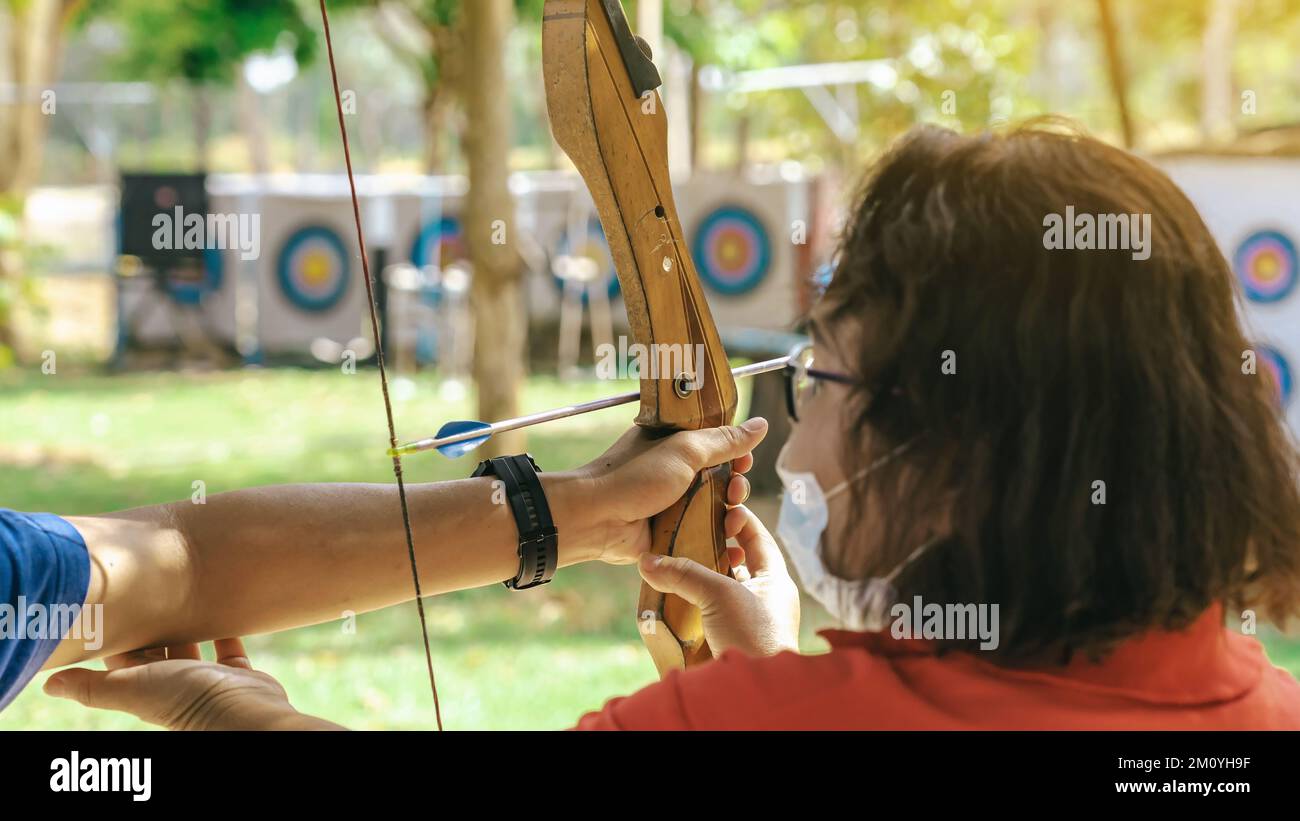 Female teacher teaches student to aim at goal. An archer teaching young ...
