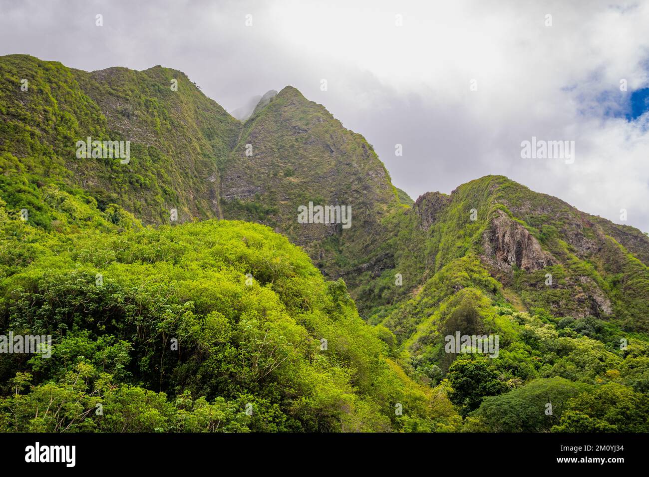 Mountain peaks below a stormy sky above a tropical forest in the Iao ...