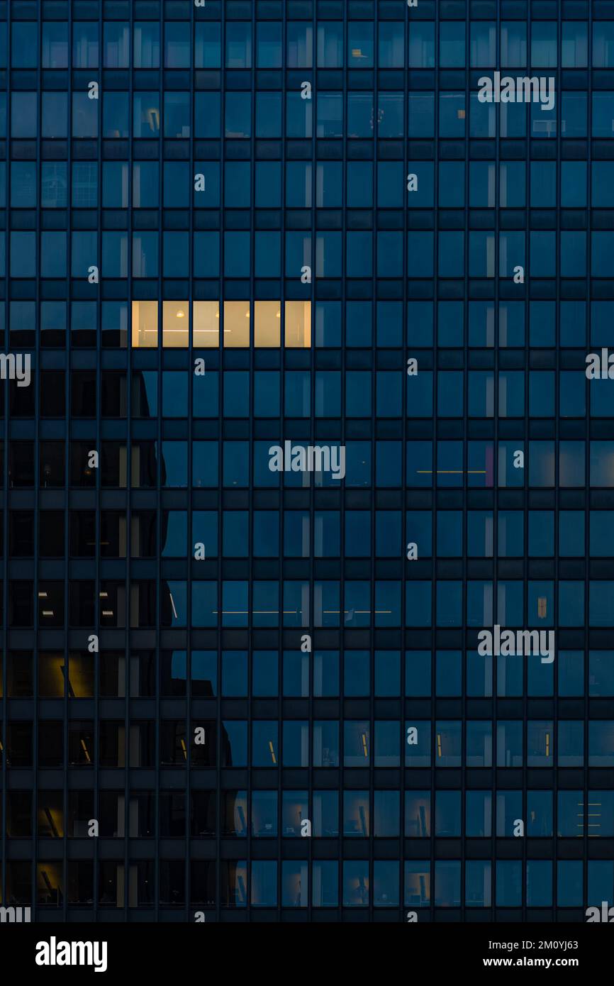 Vertical view of office building at night with one set of windows ...