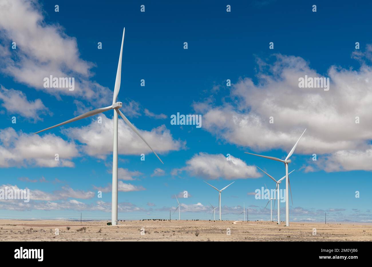 Wind farm producing green energy under a beautiful blue sky with fluffy ...