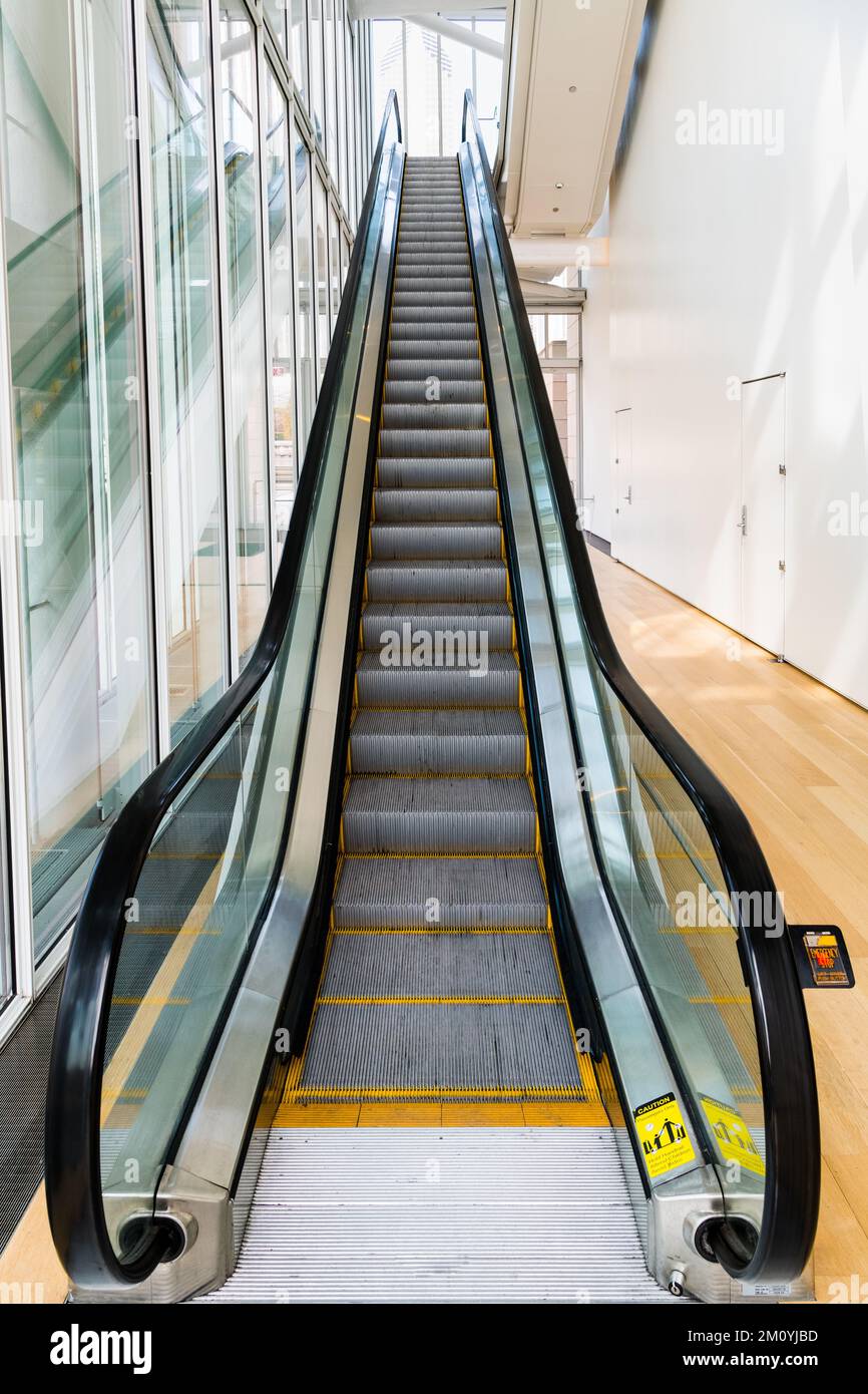 Vertical view of an escalator in the interior of a modern building with ...