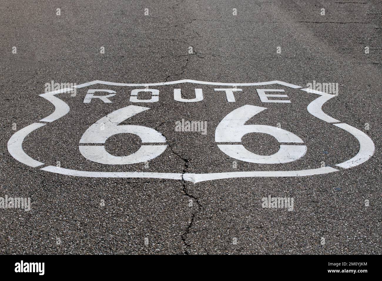 Route 66 symbol painted in white on the cracked, black asphalt of ...