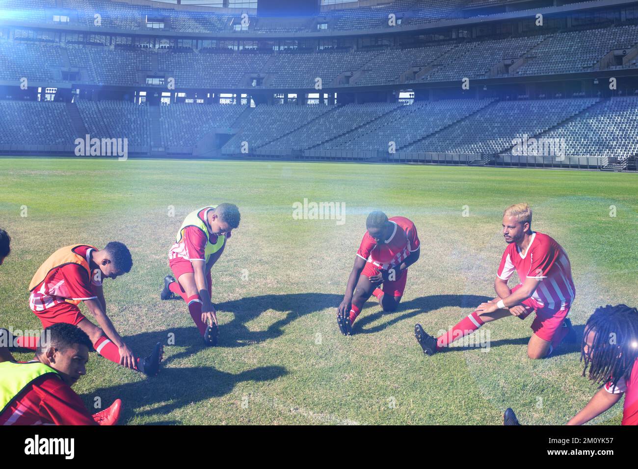 Team of multiracial male players exercising in circle at soccer field ...