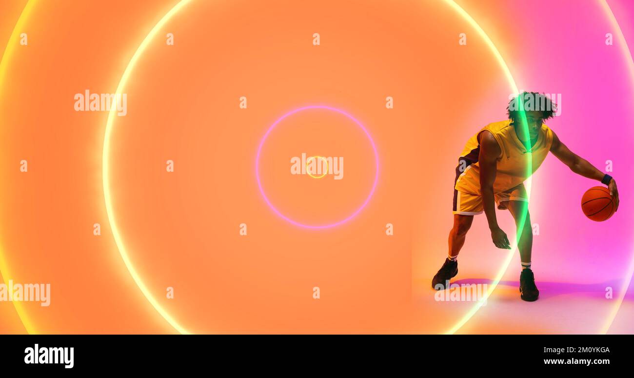 Composite of biracial basketball player dribbling ball by illuminated ...