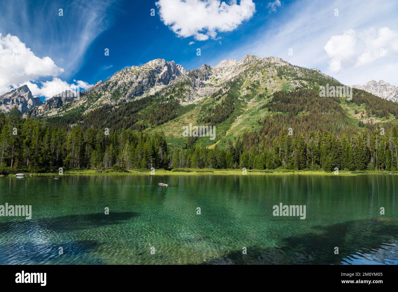 Mountains and dramatic sky above the clear, calm waters of String Lake ...