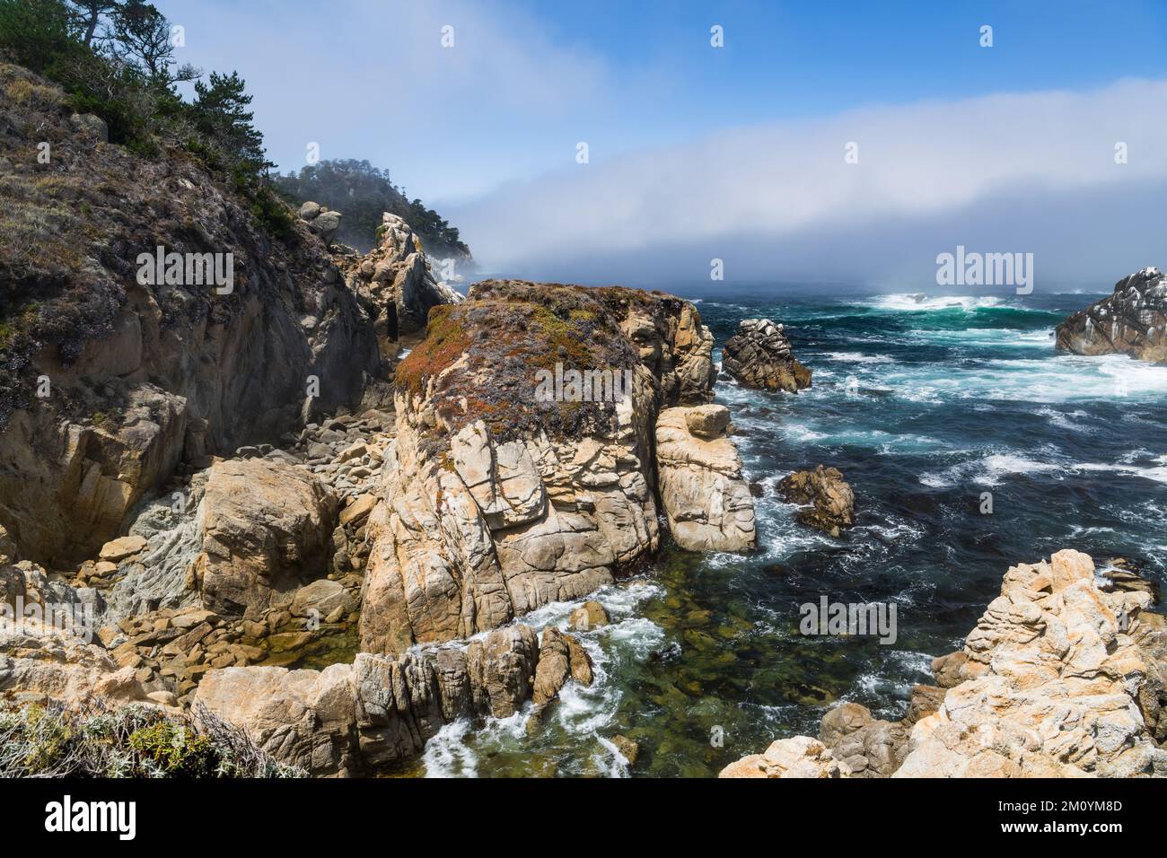 Granite cliffs and boulders above the sea and fog at Point Lobos State ...