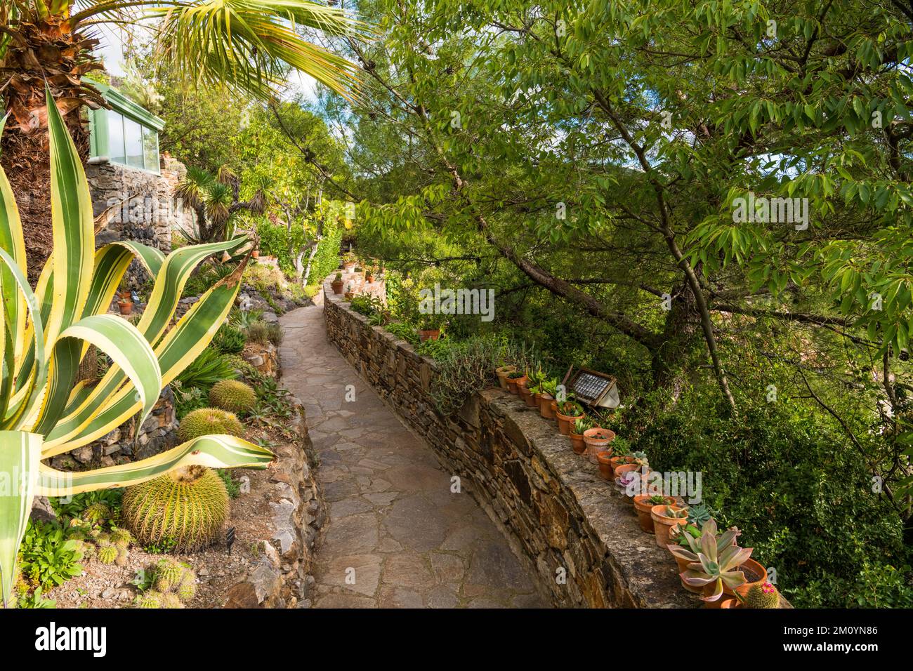 Path lined with flower pots through a garden in the village of ...