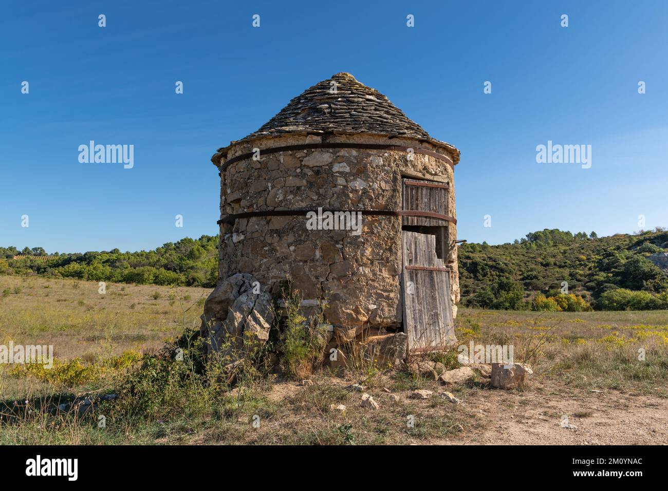 Old, round, stone farm building in a rural setting of fields and hills ...