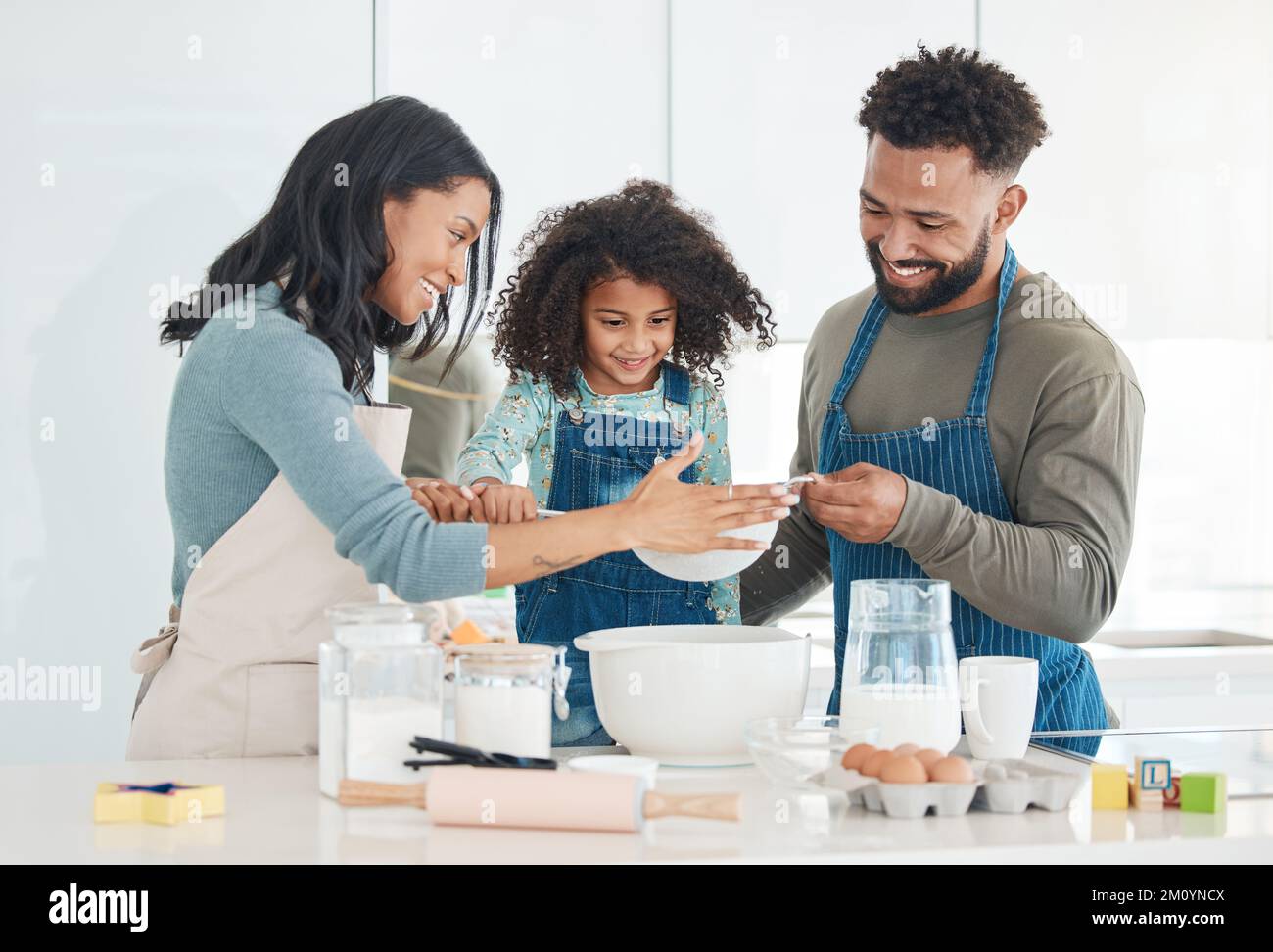 Baking up a storm. an affectionate young couple and their daughter baking in the kitchen at home ...