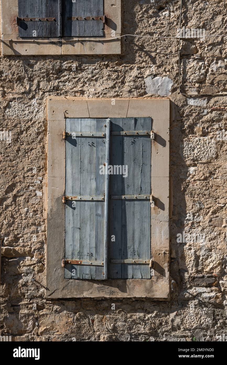 Rustic blue wood shutters and window set in a stone wall of an old ...