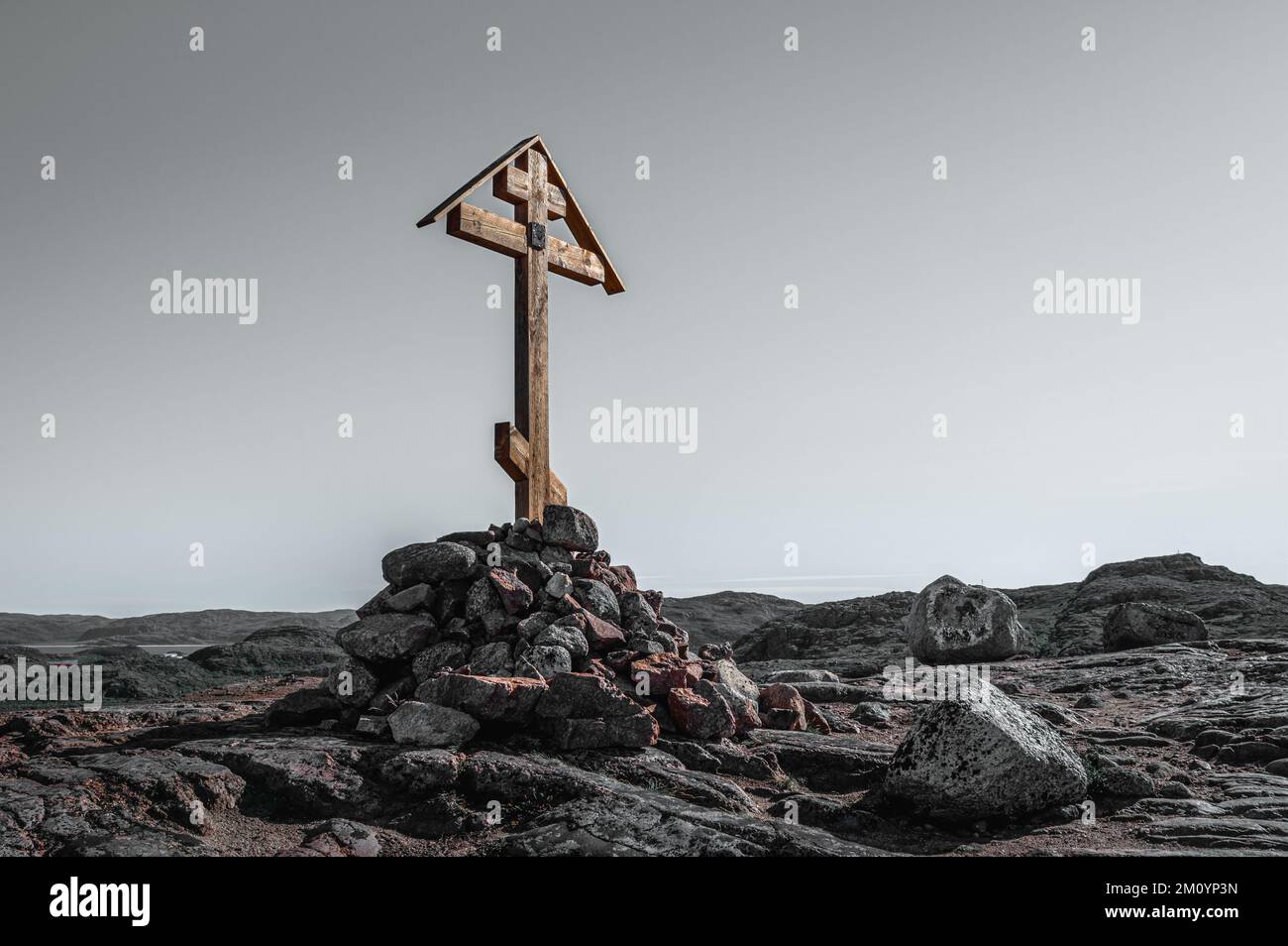 Wooden cross upon an ancient burial site amid desolate mountains ...