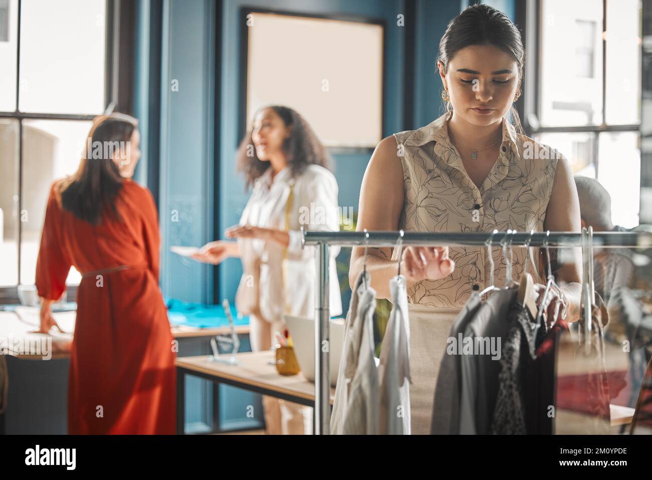 What should I get. a young woman sorting through clothes at a boutique ...
