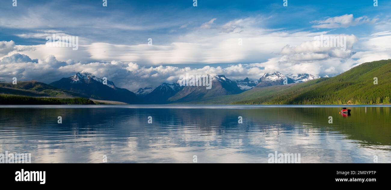 Panorama of snow-capped mountain peaks and red boat under dramatic sky ...