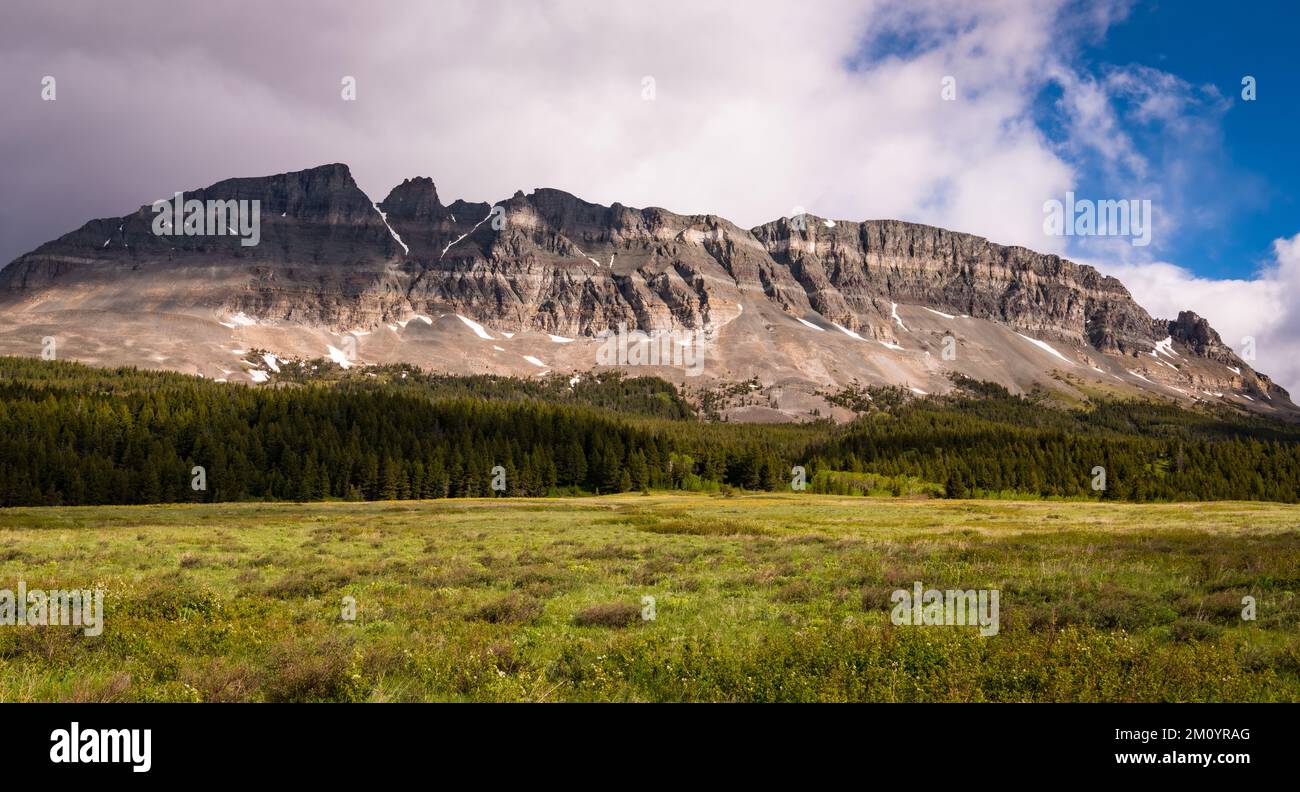 Panorama of a rugged mountain range and grassy meadow under a dramatic ...