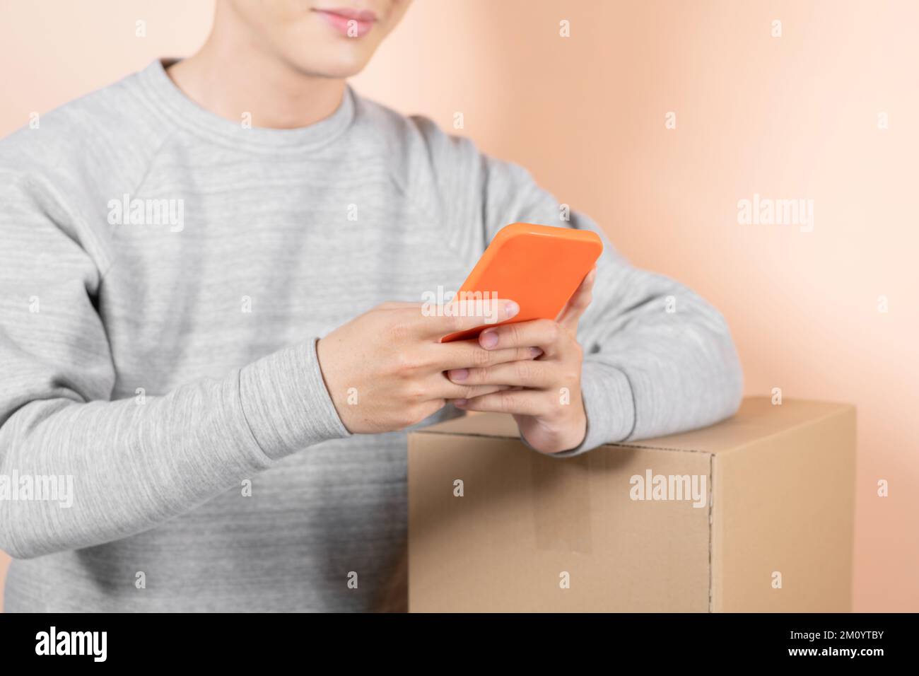 Happy delivery man using cellphone while standing with parcel boxes ...