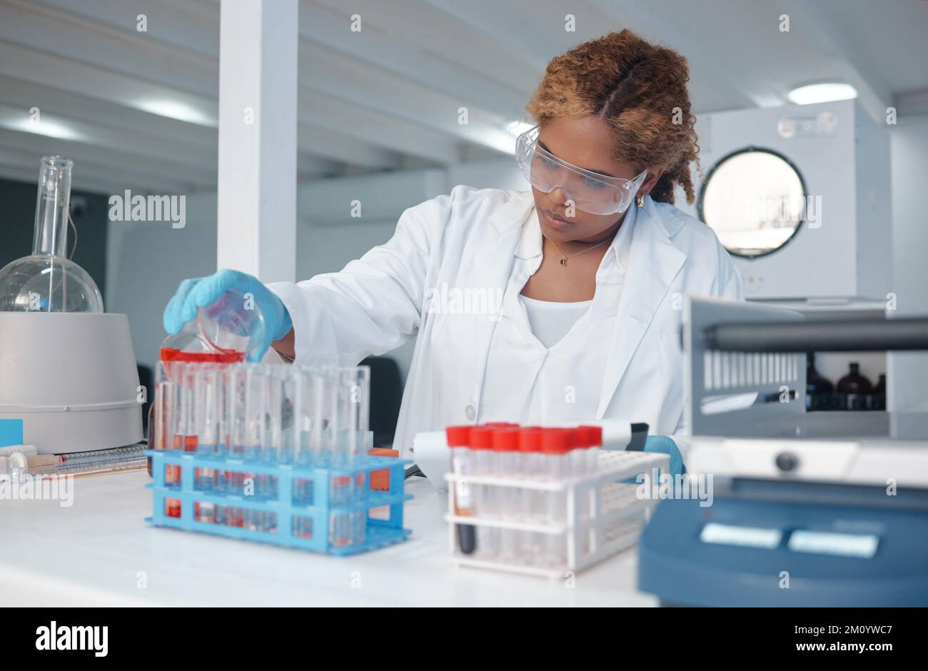 handle with extreme care. a young female lab worker filling test tubes ...