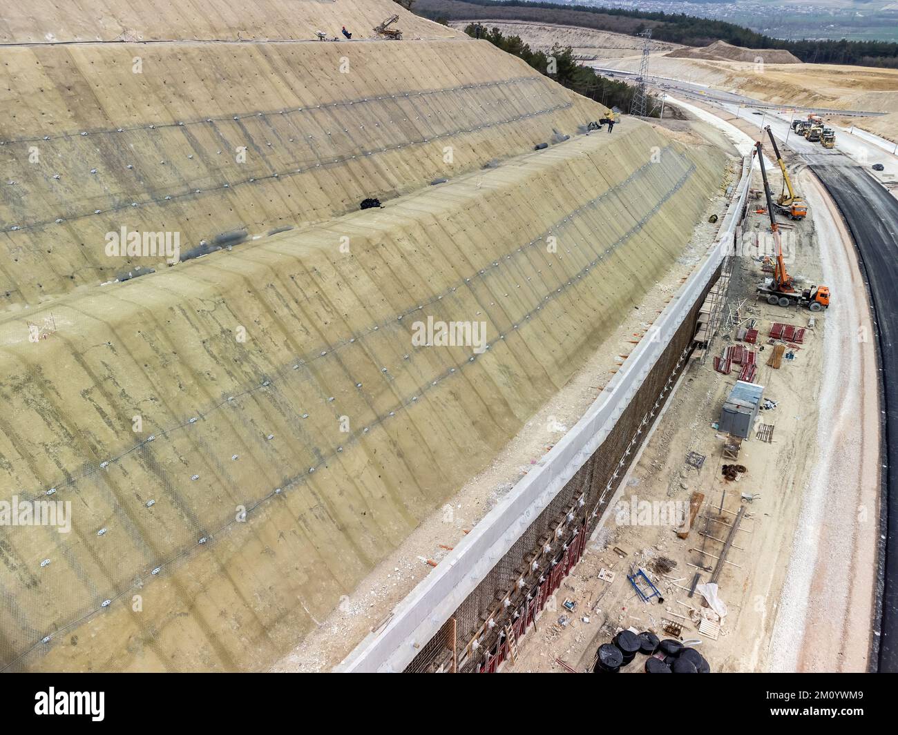 Mountain road constraction. Workers reinforce the slope over the new ...