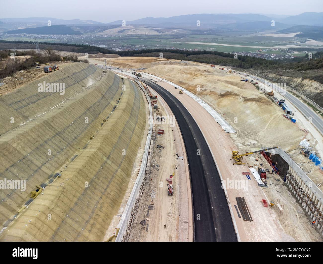 Mountain road constraction. Workers reinforce the slope over the new ...