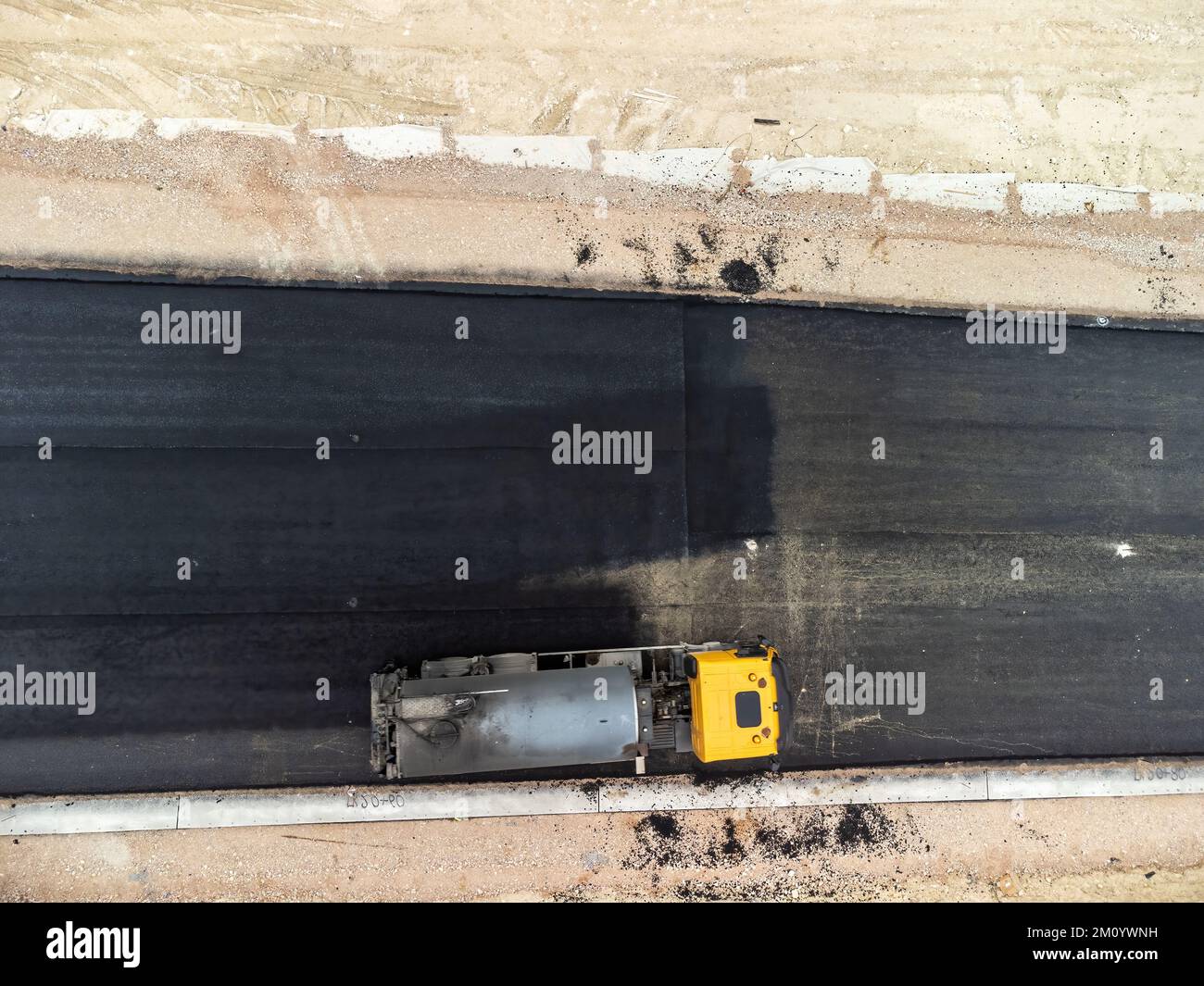 yellow truck pouring bitumen over a new road. Aerial drone shot. Road ...