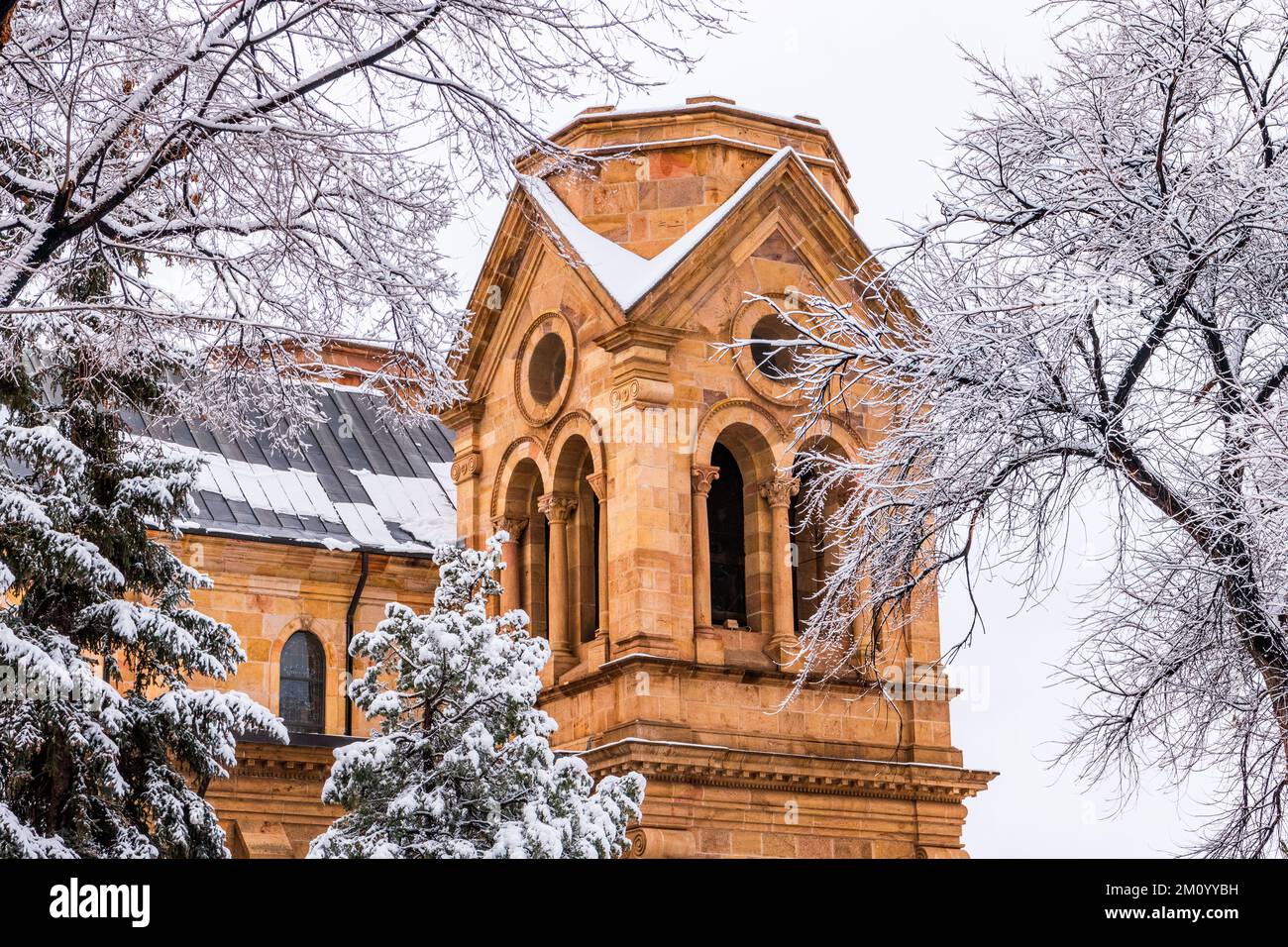 Snowy winter scene of church bell tower and snow-covered trees in Santa ...