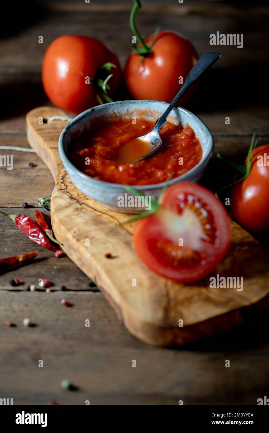 Strained tomatoes in small bowls on rustic cutting board Stock Photo ...