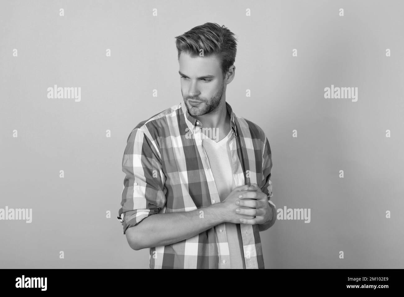 Handsome unshaven man with serious face looking down yellow background ...