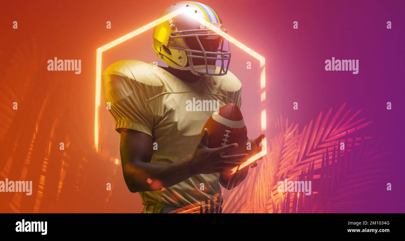 American football player holding ball standing by illuminated hexagon ...