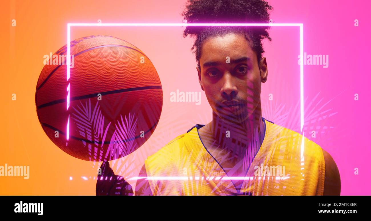 Portrait of handsome biracial basketball player spinning ball on finger ...