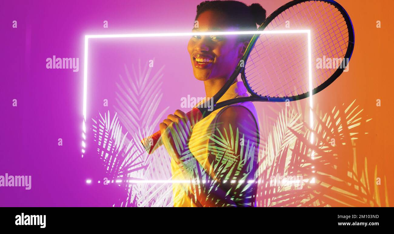 Biracial smiling female player with tennis racket standing by ...