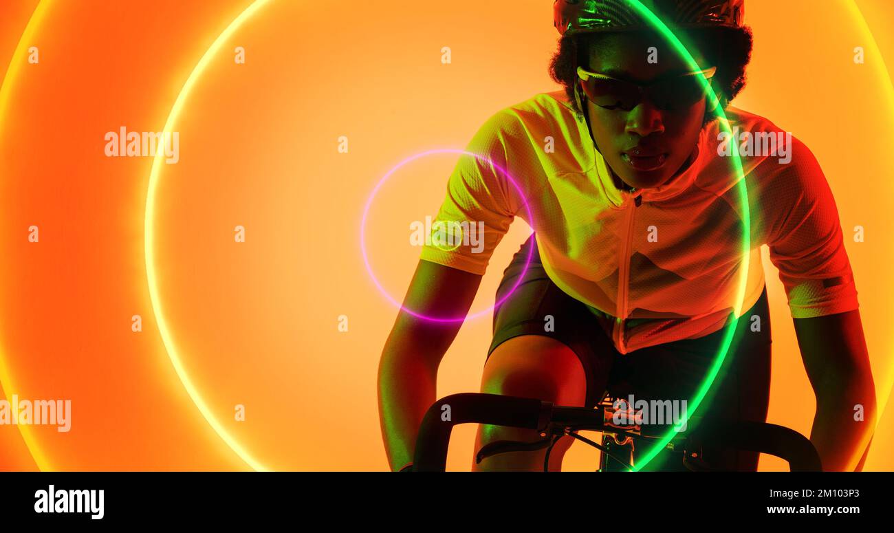 Biracial female athlete wearing glasses and helmet riding bike over illuminated colorful circles ...