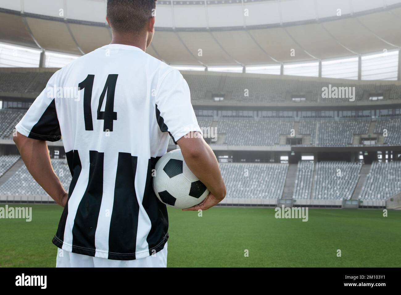 Rear view of number 14 player with soccer ball in stadium, copy space ...