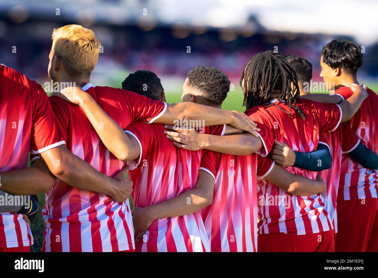 Team of multiracial male players in sports clothing with arms around at ...