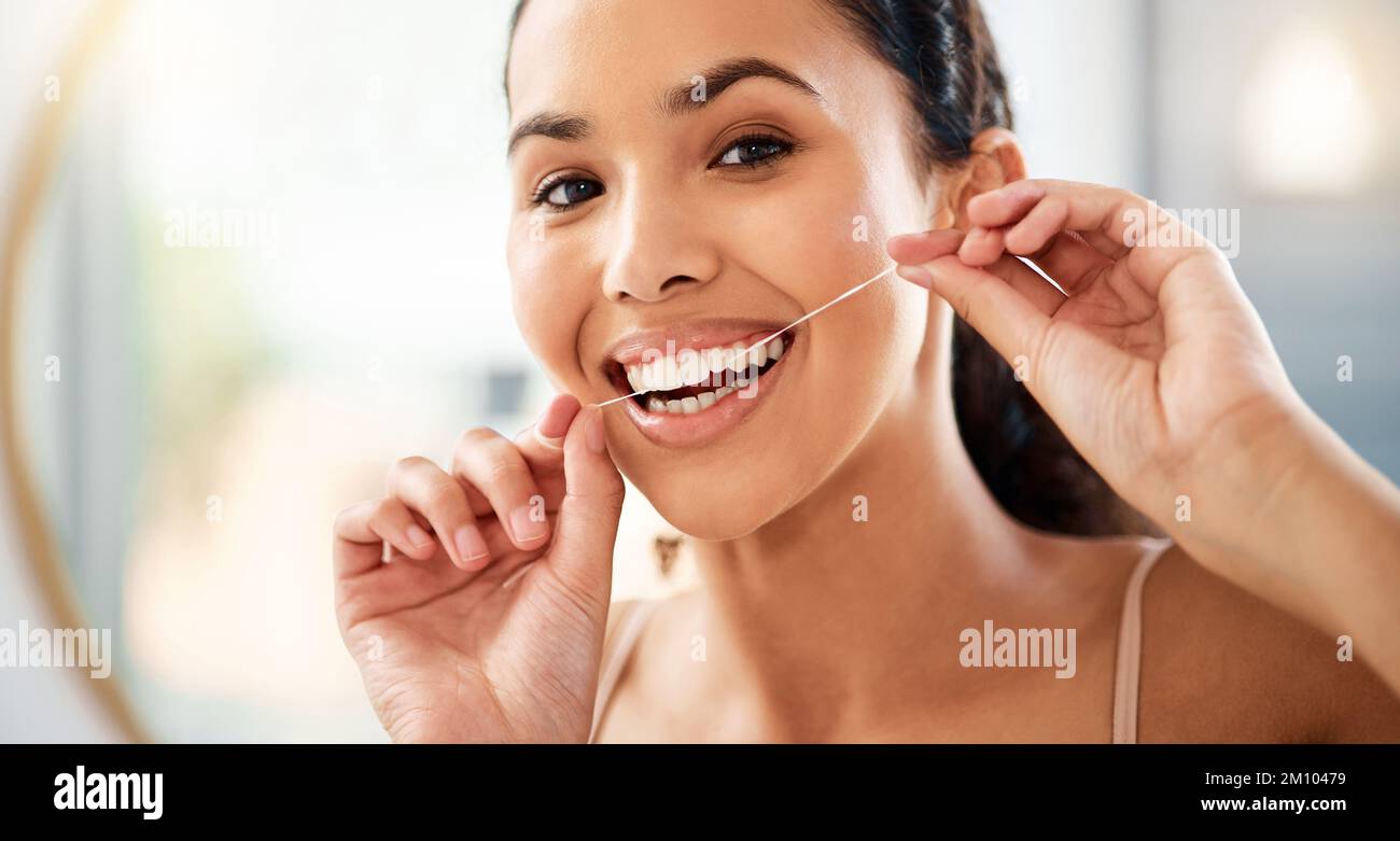 Keep on flossing. a young woman flossing her teeth at home Stock Photo ...