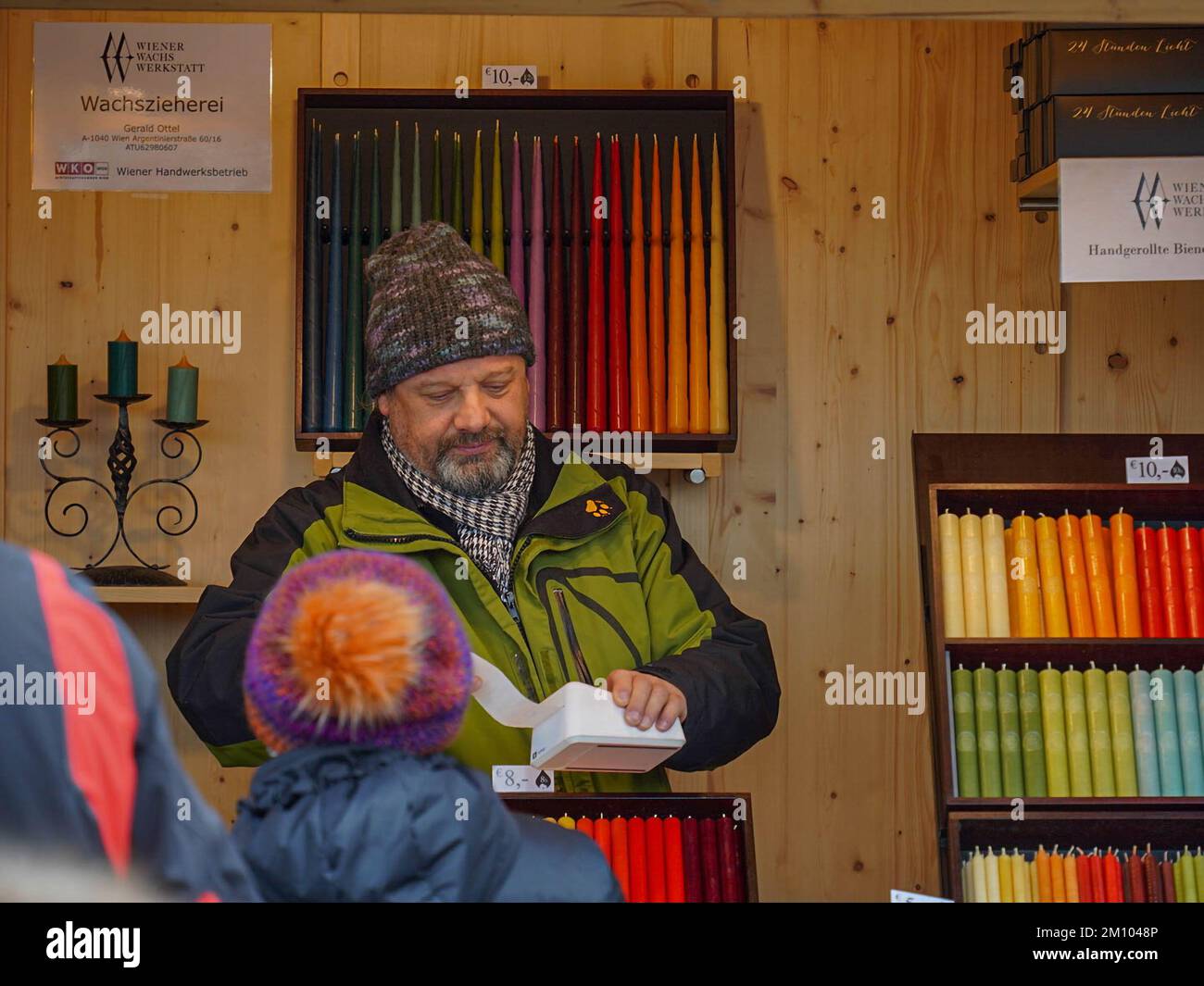 A man sells sets of colorful candles in kiosk at Viennese Christmasfair ...