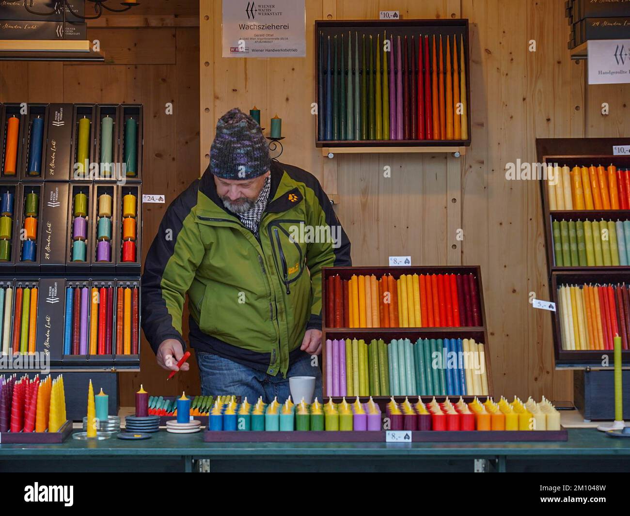 A man sells sets of colorful candles in kiosk at Viennese Christmasfair ...