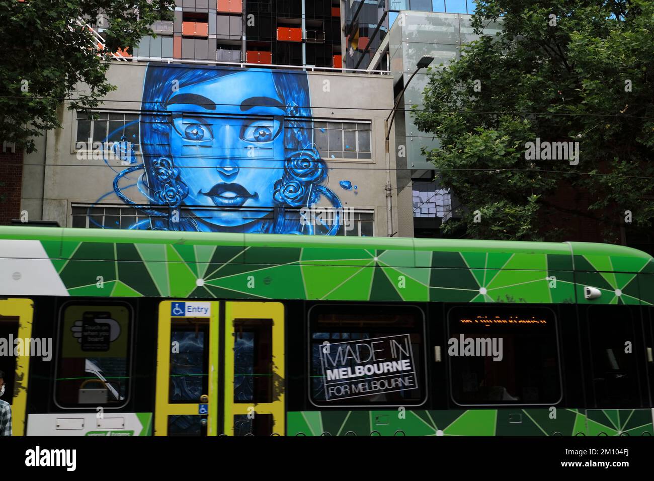 Green Melbourne tram passing by blue woman face graffiti Stock Photo ...
