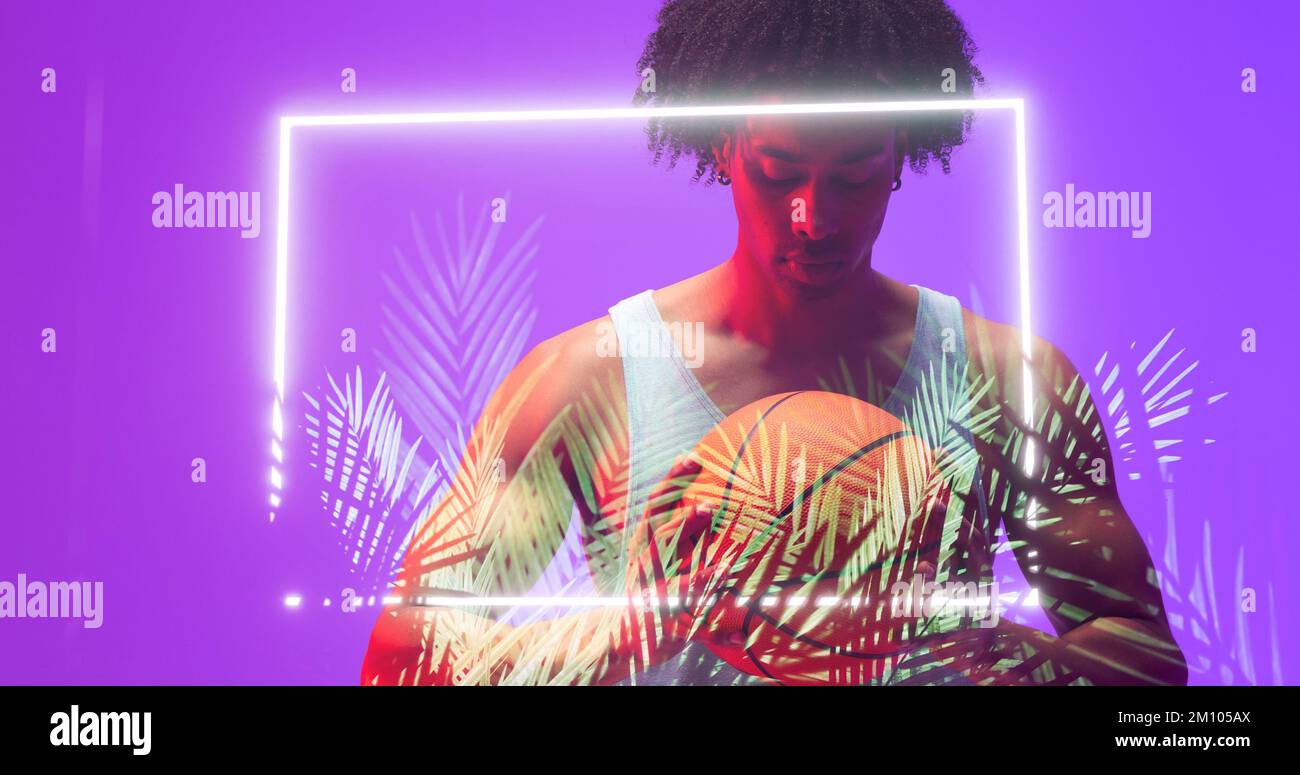 Biracial basketball player with afro hair holding ball by illuminated ...