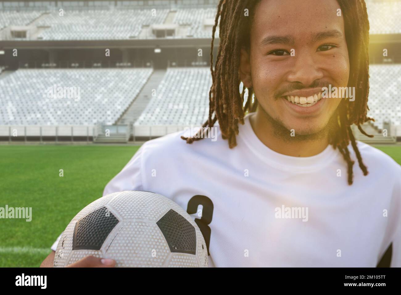 Portrait of smiling african american soccer player with ball at stadium ...