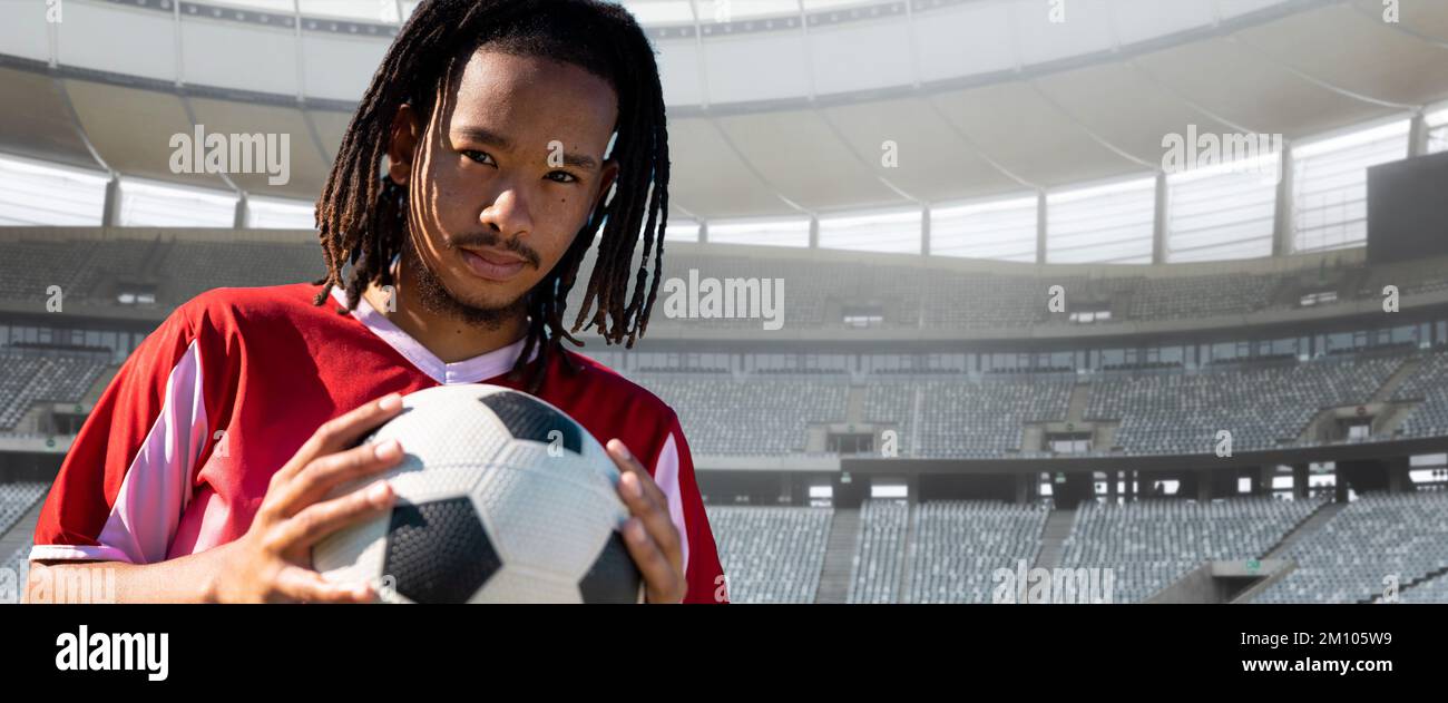 Image of biracial football player holding football in empty sports ...