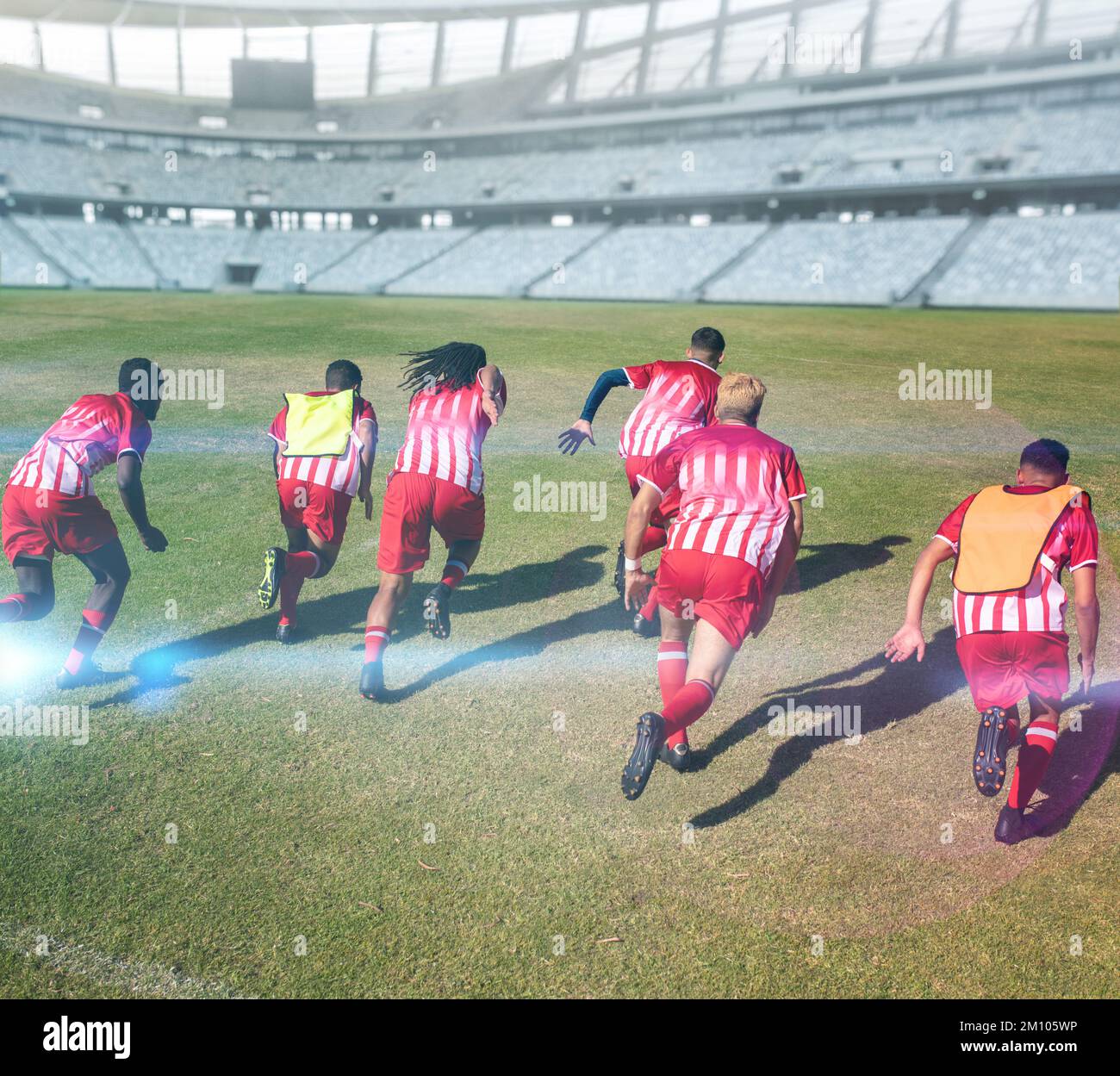 Rear view of multiracial male soccer players in sports clothing running ...