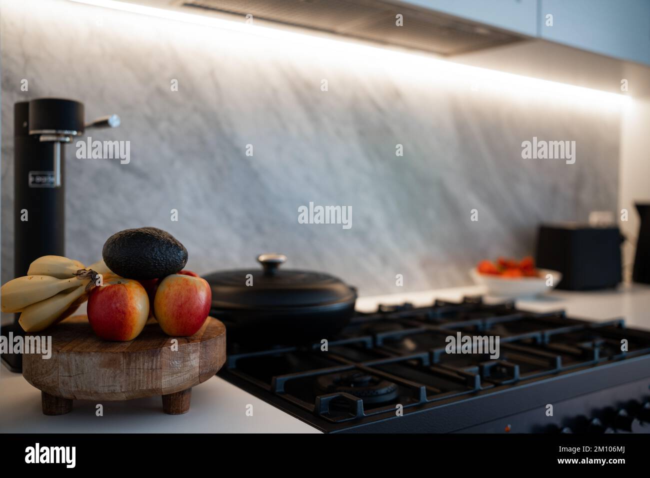 A modern kitchen with fruits by a black cooktop Stock Photo - Alamy