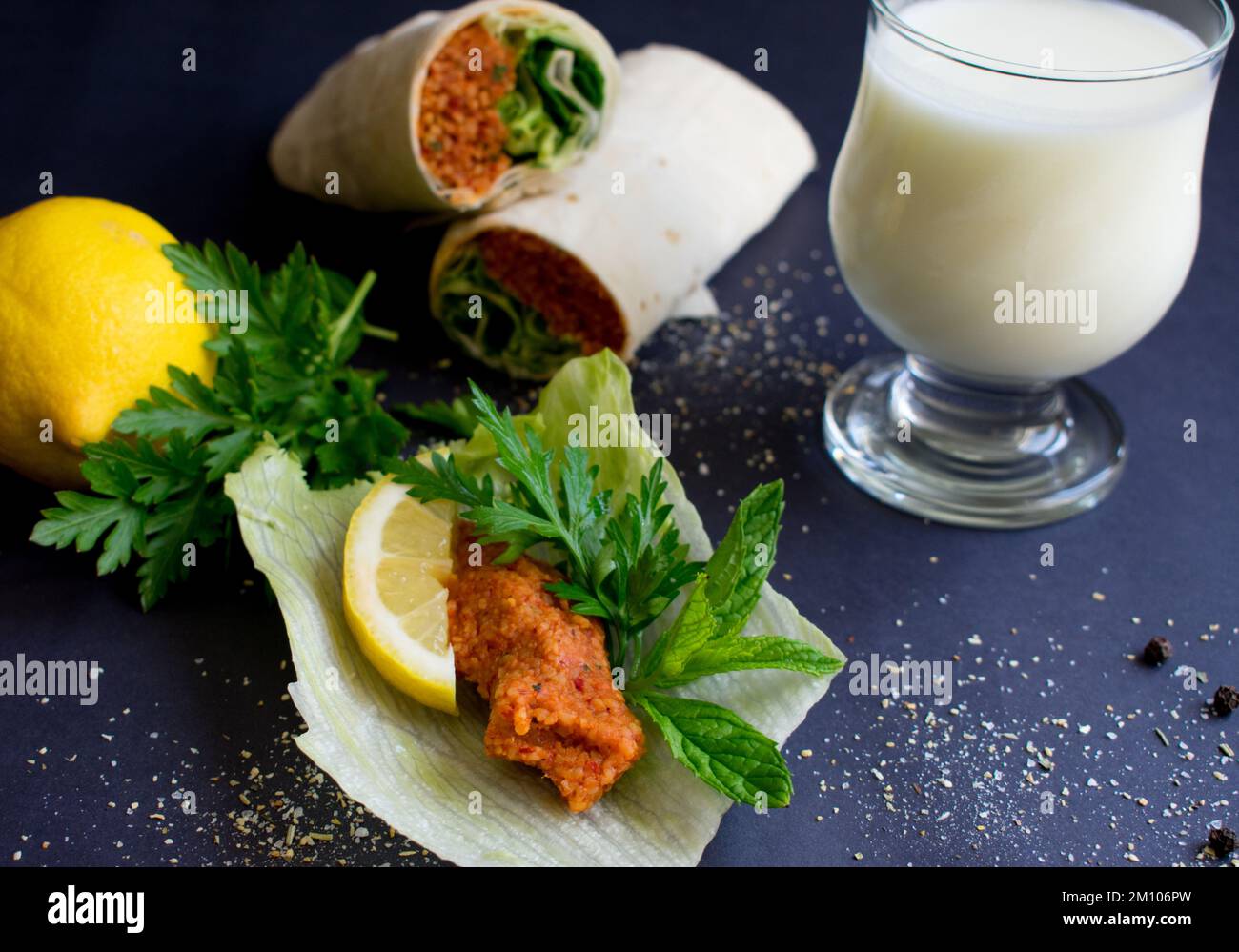 Presentation of raw meatballs on lettuce and lemon on black background ...