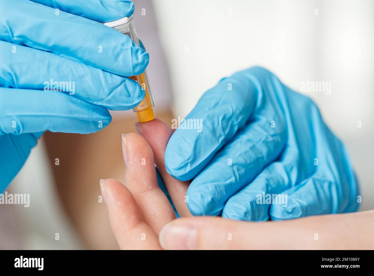 Doctor piercing patients finger with lancet in clinic closeup. Taking ...