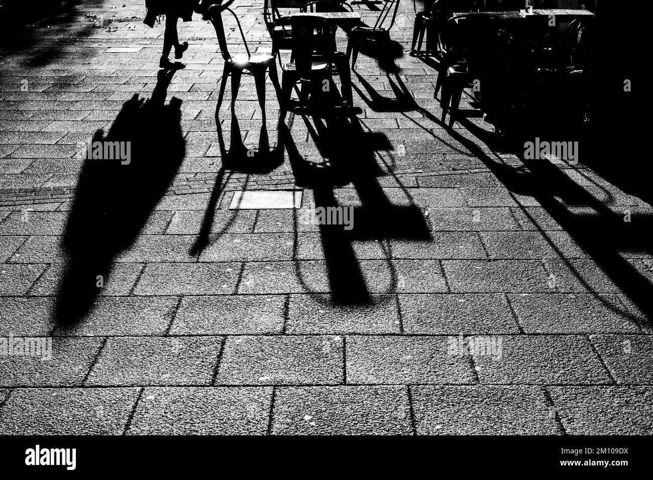 Long shadows of chairs and tables and figures in black and white ...