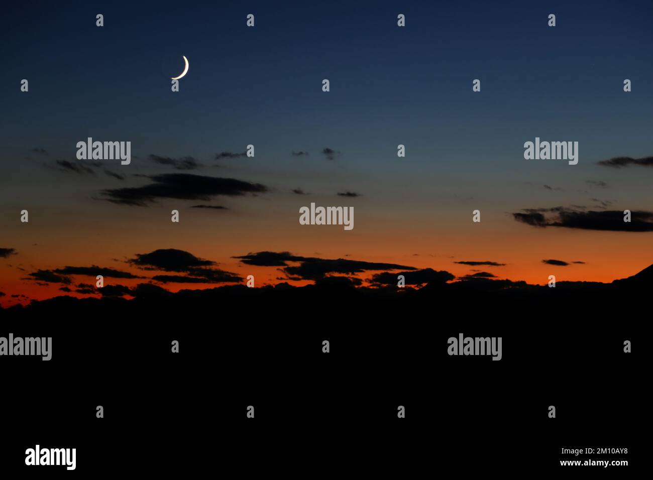 small crescent moon during sunset and the romantic colors of the sky ...