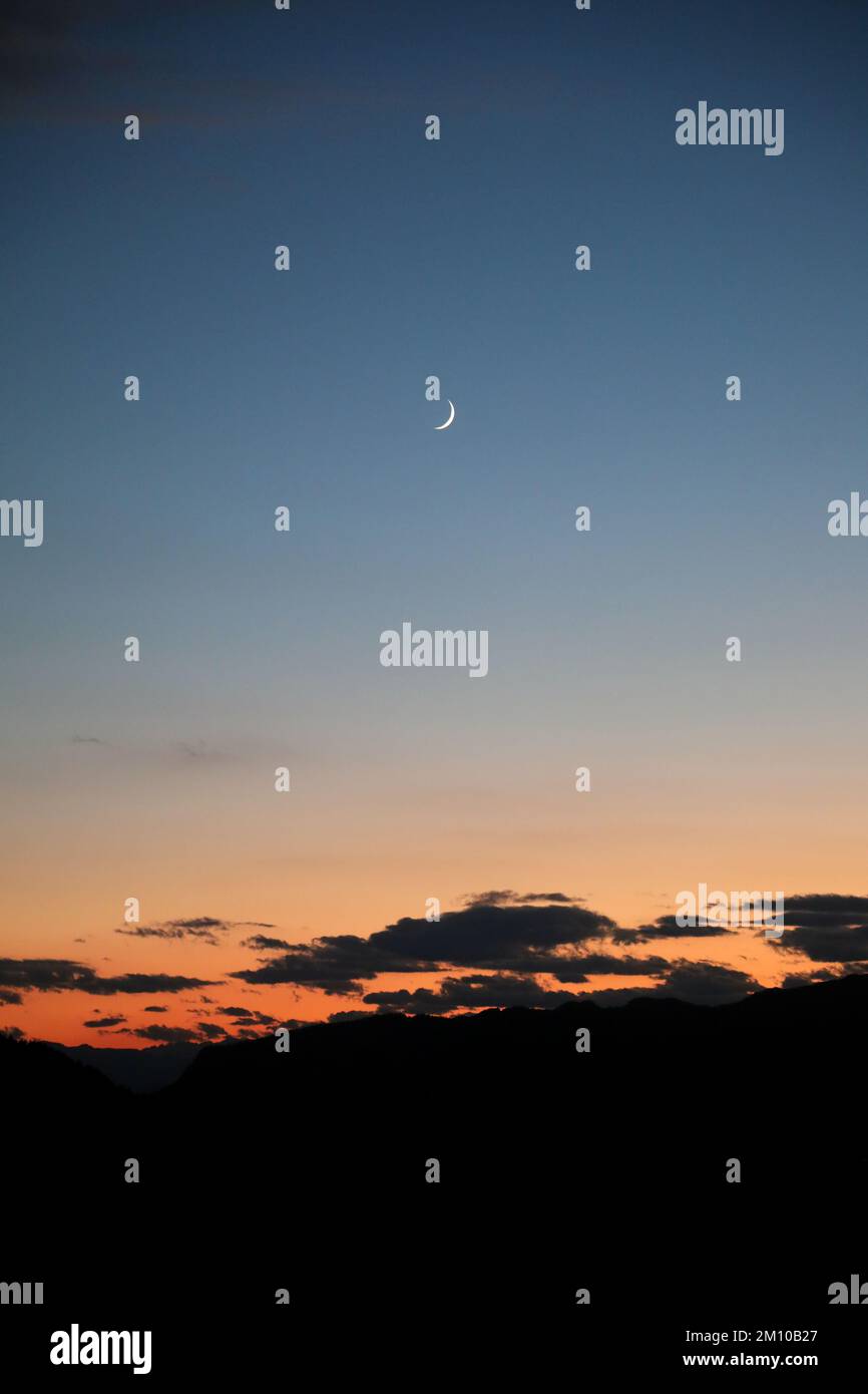 small crescent moon during sunset and the romantic colors of the sky ...