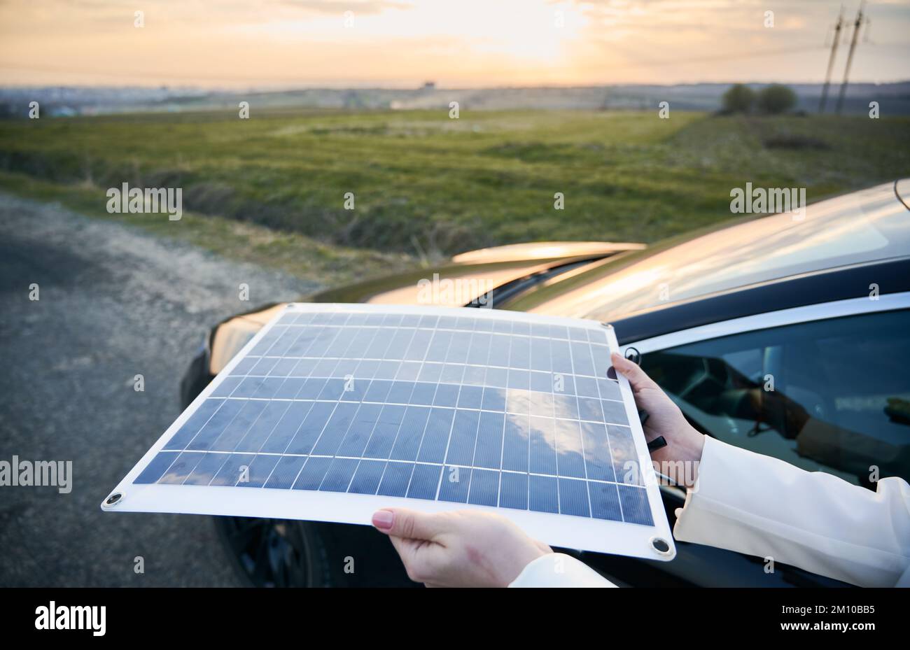 Close up one solar battery in women's hands on the background of car ...