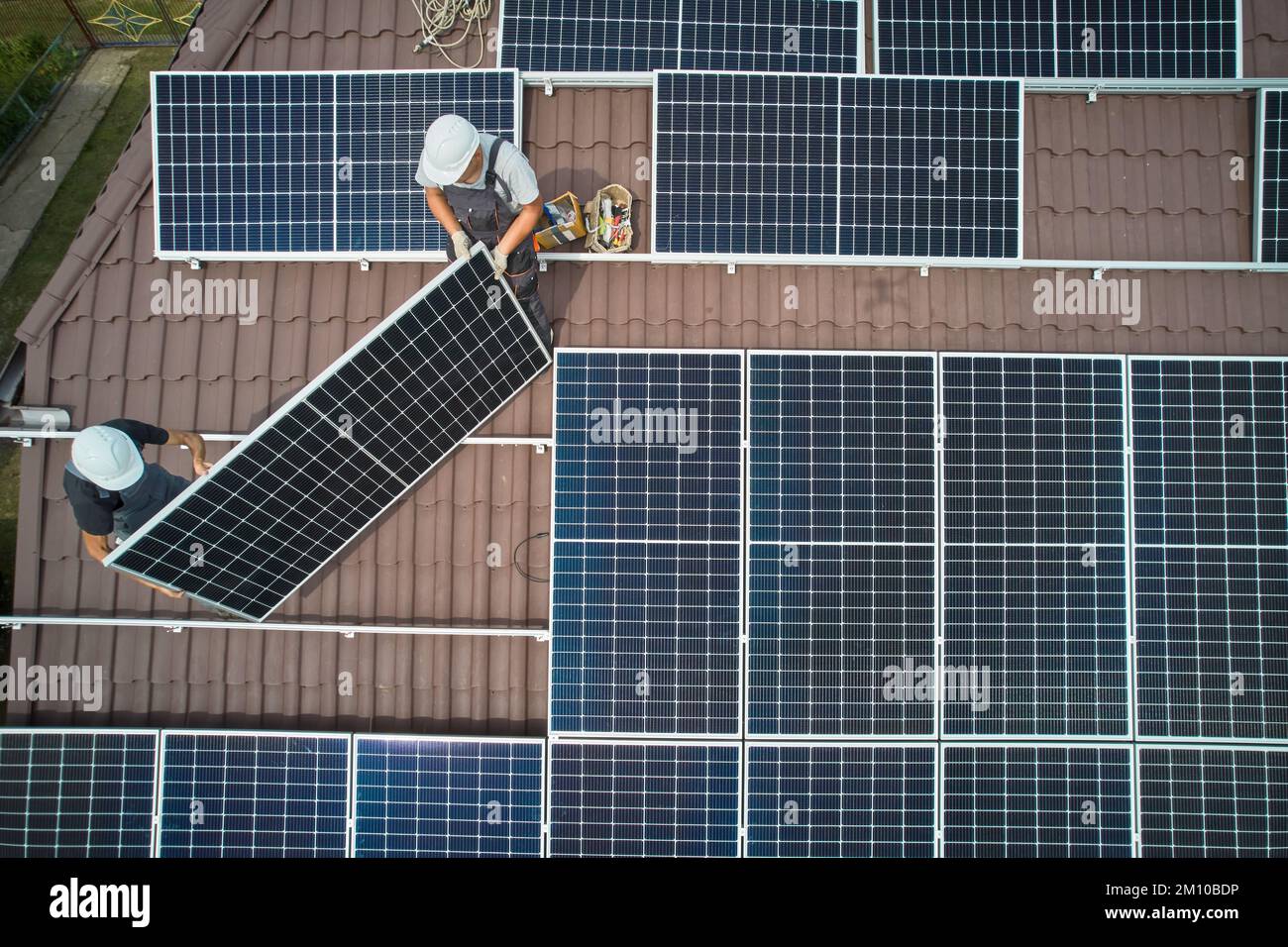 Men workers installing photovoltaic solar moduls on roof of house ...