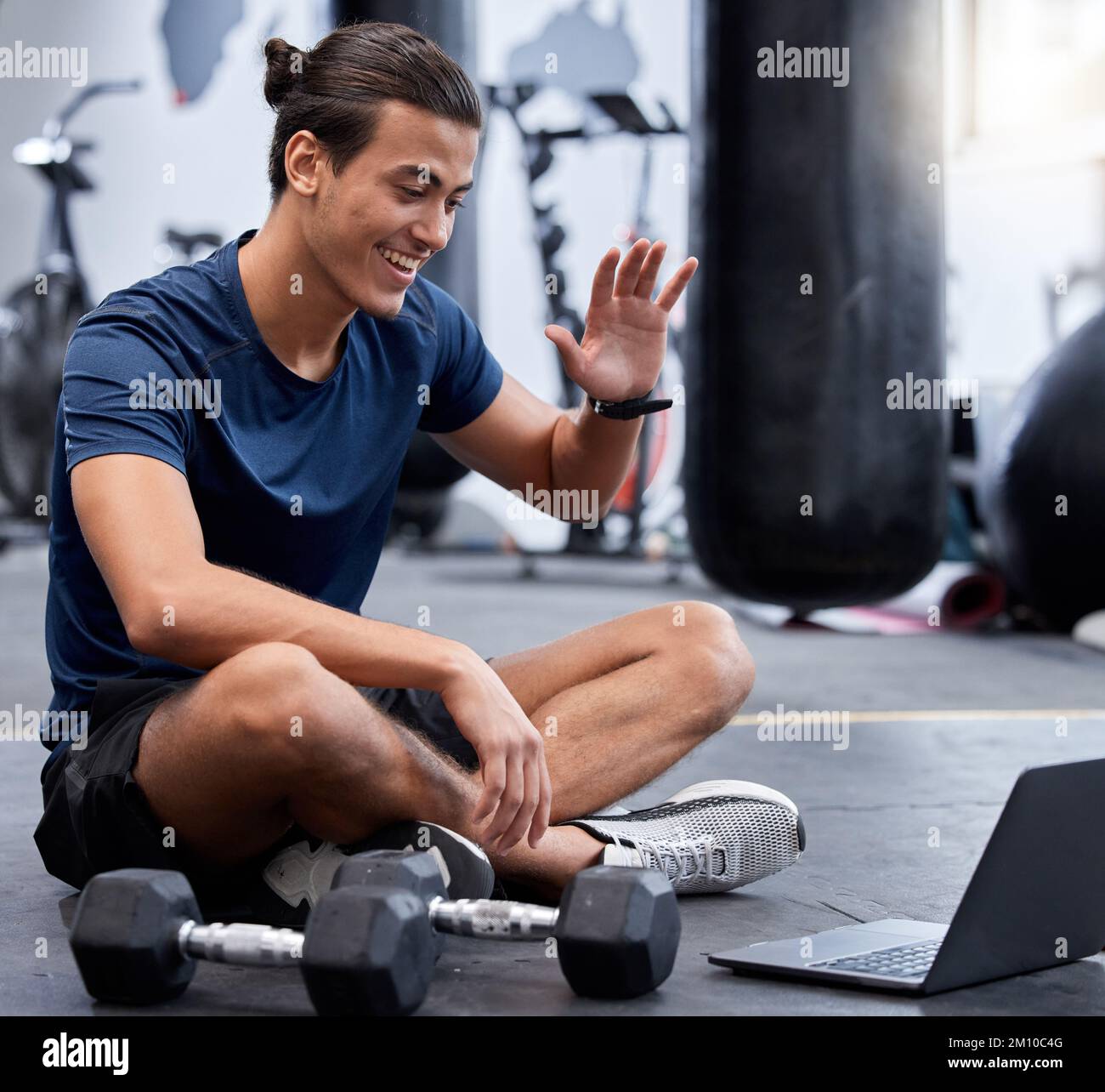 Man, laptop and wave for video call in gym with smile rest on floor ...